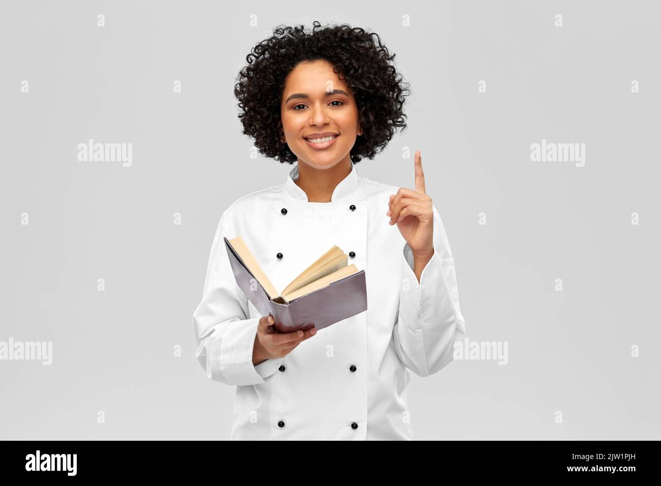 happy female chef in white toque reading cook book Stock Photo - Alamy