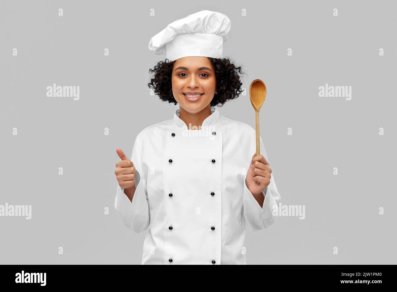 smiling female chef with spoon showing thumbs up Stock Photo - Alamy