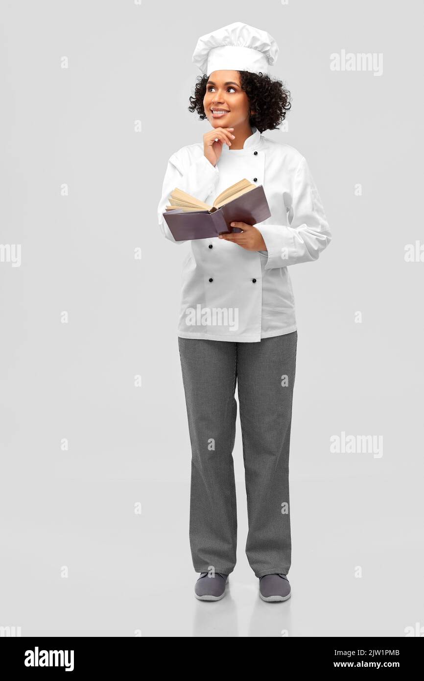 happy female chef in white toque reading cook book Stock Photo - Alamy