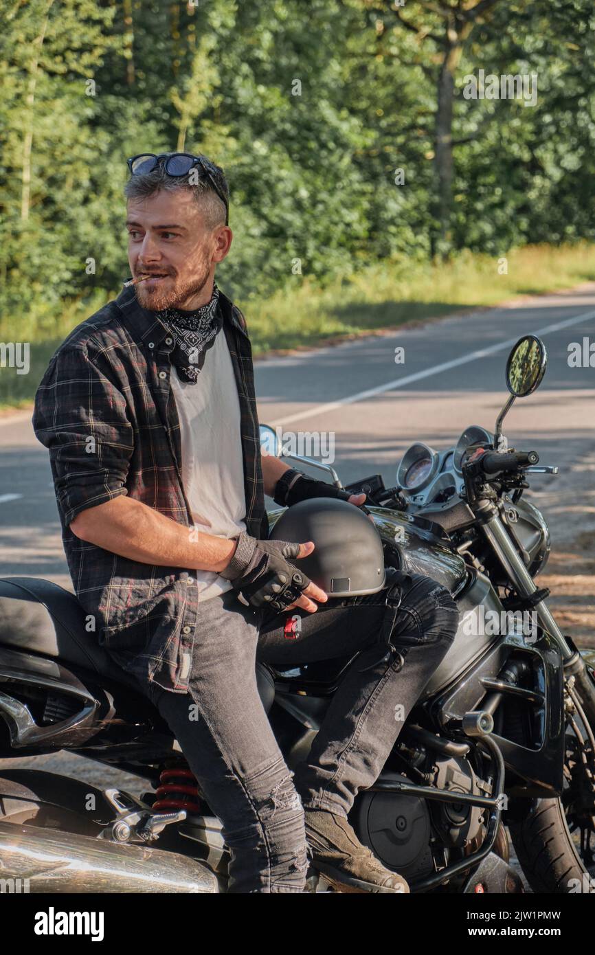Young male biker travels on a motorcycle alone, stopped and smoking on ...