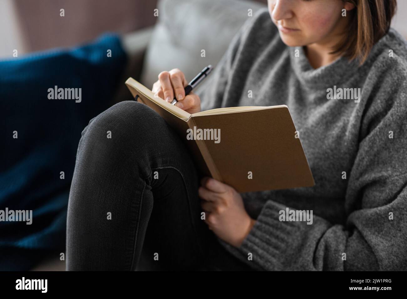 sad woman with diary sitting on sofa at home Stock Photo - Alamy