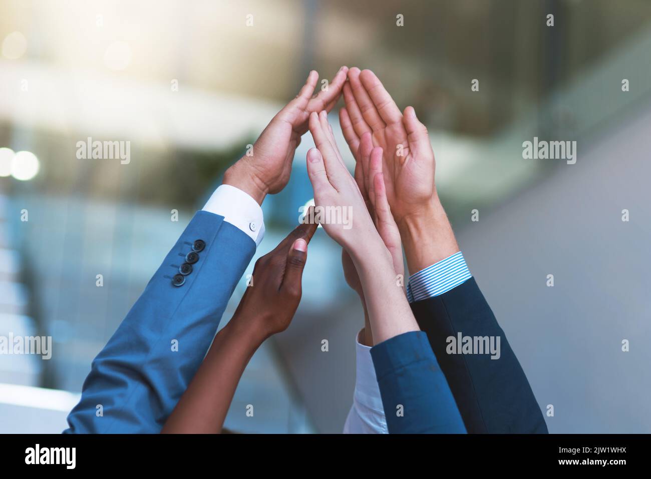 United for success. a group of people putting their hands up together ...