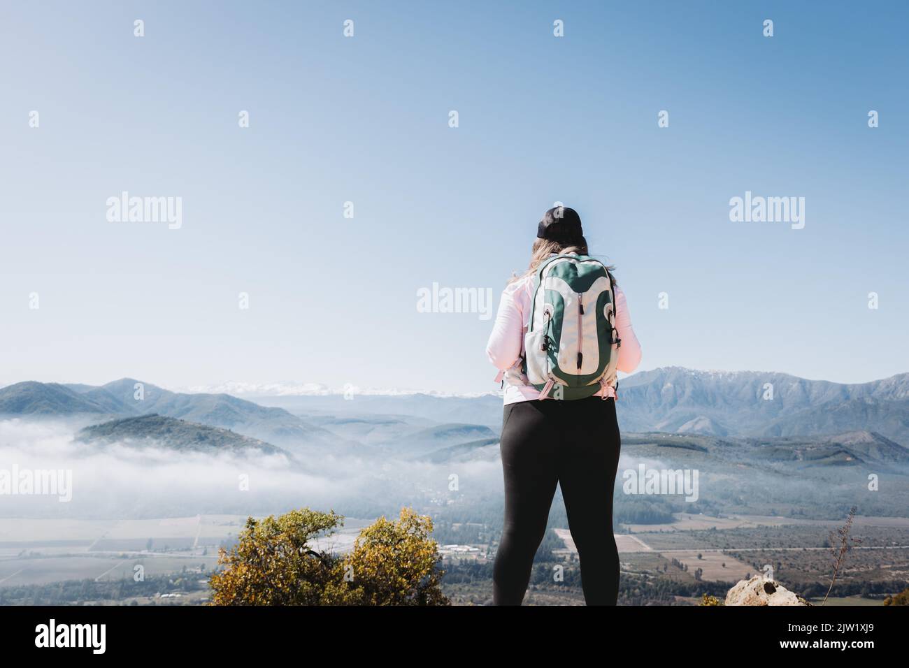 Rear view young latin plus size woman with backpack on, at the top of a ...