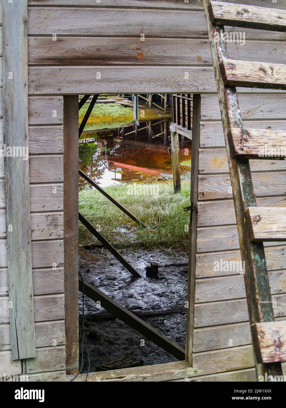 View of reflection in pond through opening in rustic timber wall at ...