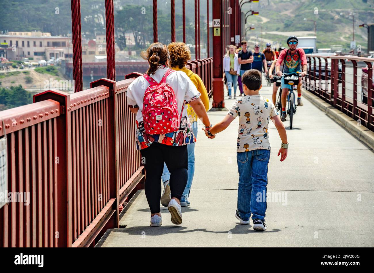 A mother and son hold hands as they calk along the sidewalk on The ...