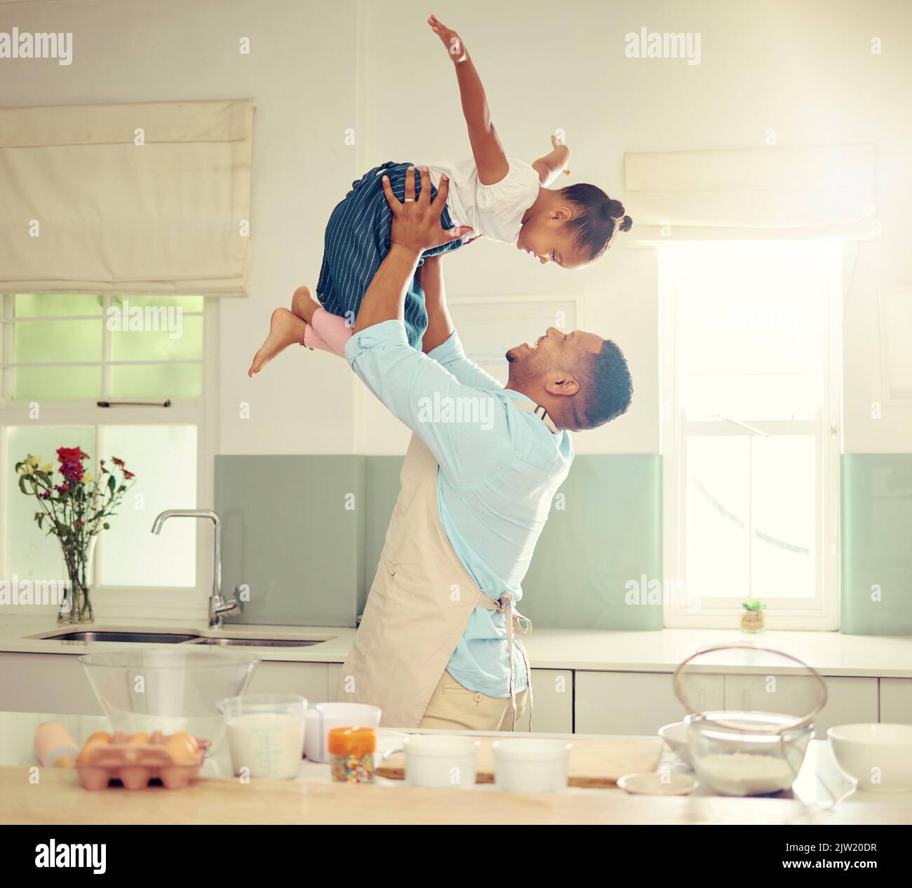 Happy black father and daughter playing in a kitchen while cooking ...