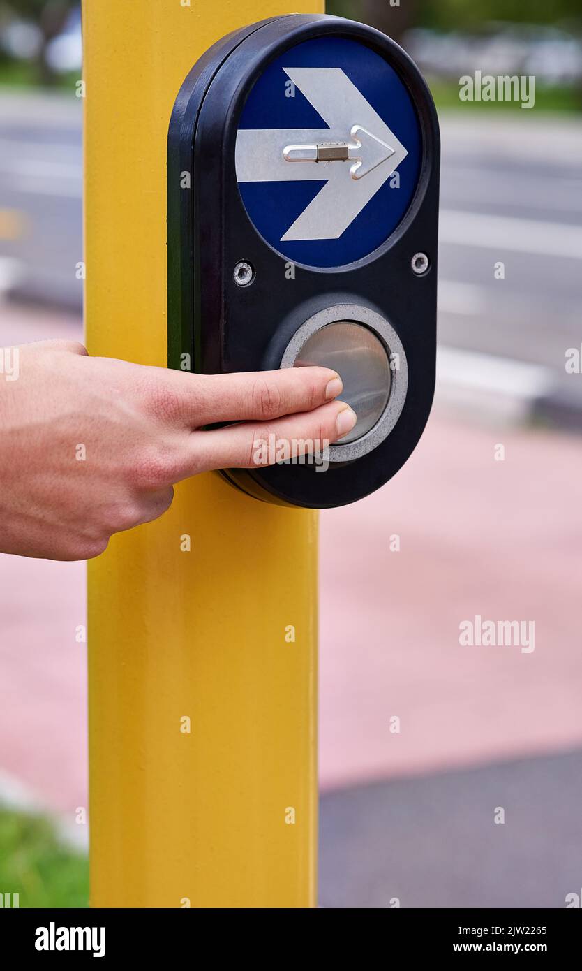 Cross with care. a mans hand pressing the crossing button at an ...