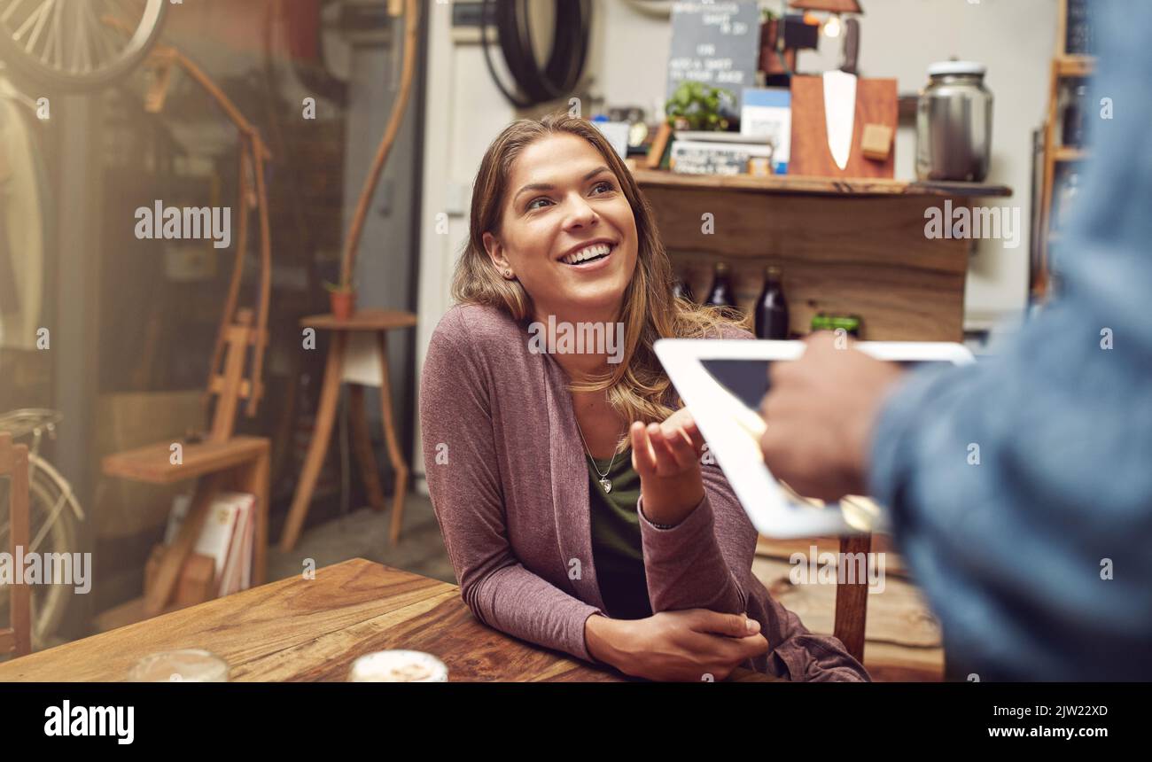 Taking orders the wireless way. a young woman placing her order with a ...