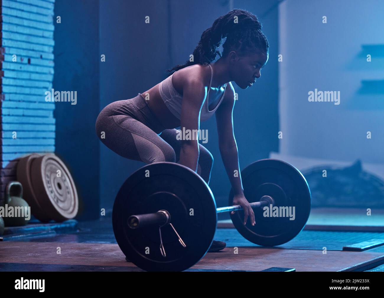Strong, black woman and focus barbell fitness to deadlift workout, heavy exercise and dark gym ...