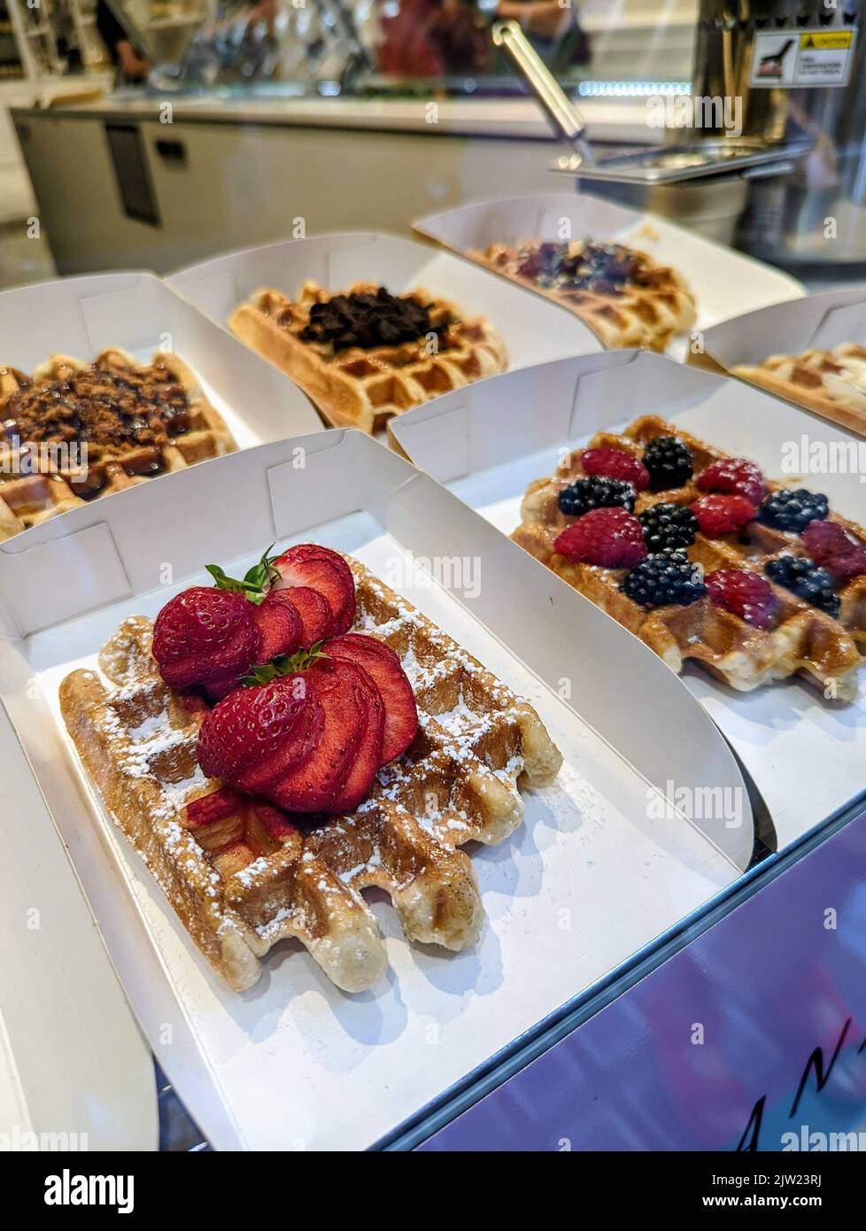 A vertical shot of waffles topped with berries with seperate packagins ...