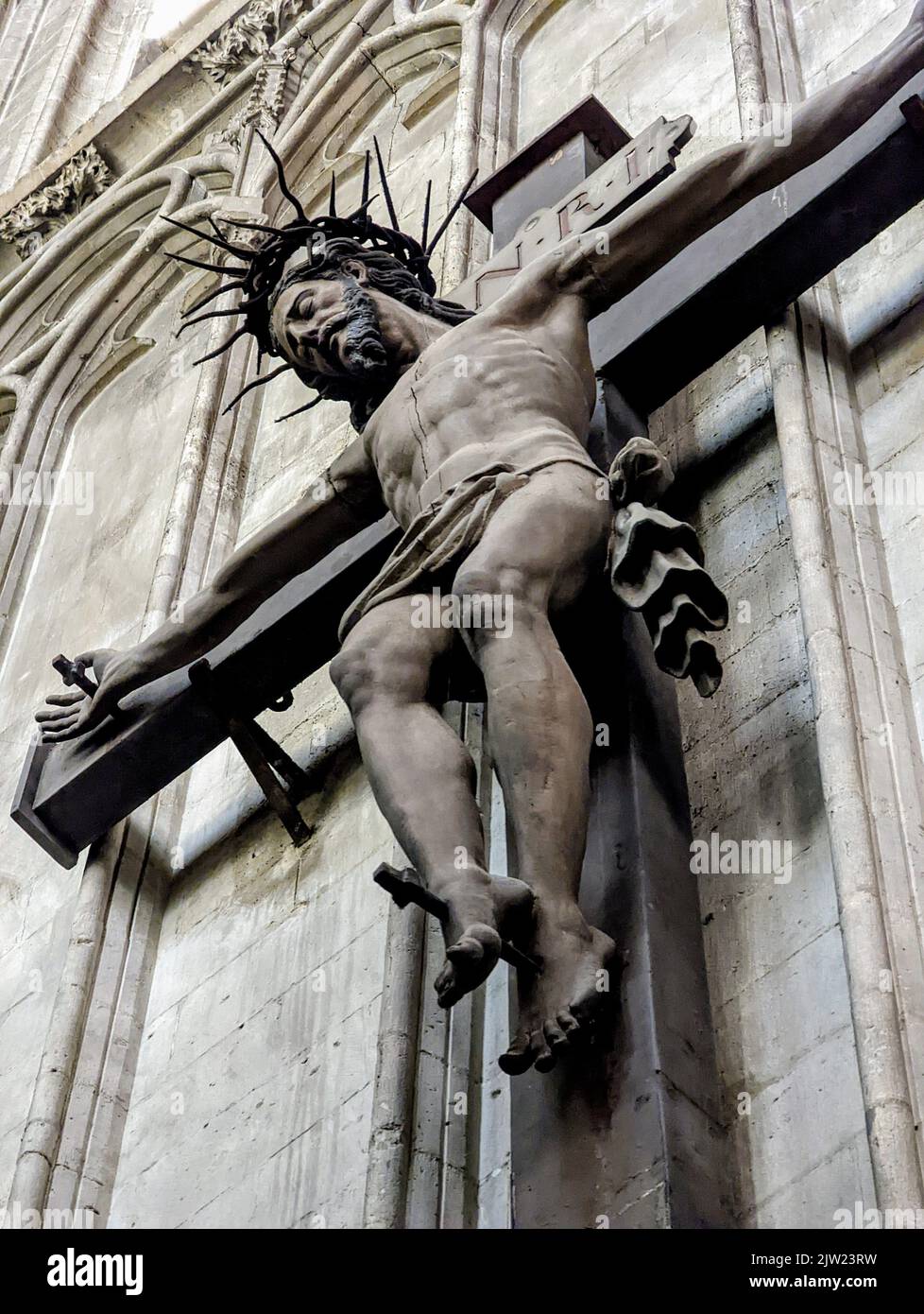 A low-angle vertical shot of Jesus's crucifixion sculpture hanging on the wall Stock Photo - Alamy