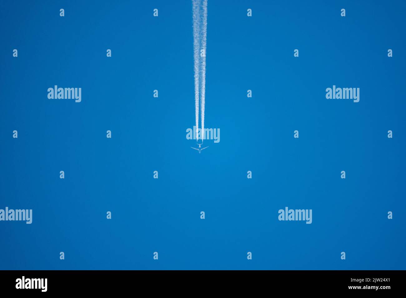 Airplane showing jetstream across blue sky Stock Photo - Alamy