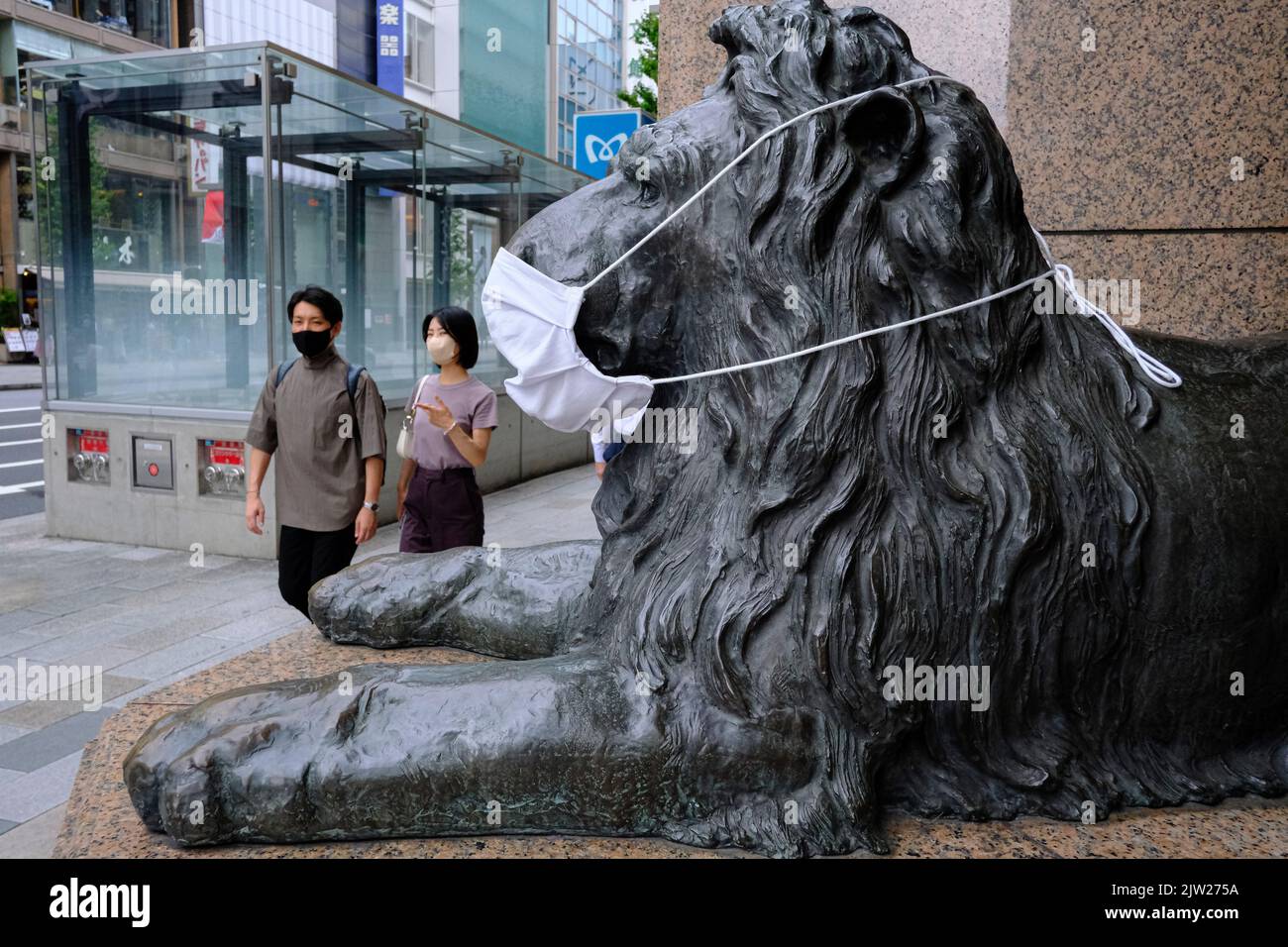 Tokyo, Japan. 24th Aug, 2022. People wearing face masks walk by a lion ...