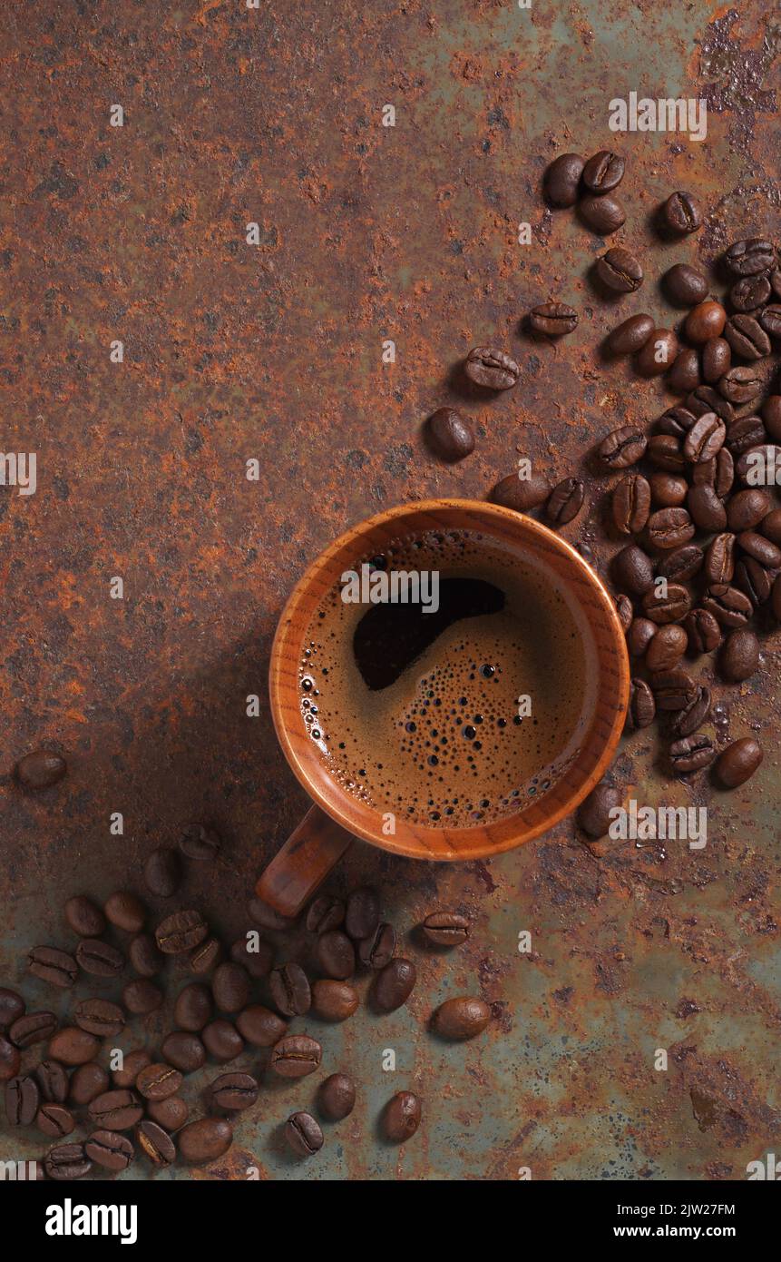 Wooden cup of coffee and beans on rusty iron background, top view with ...