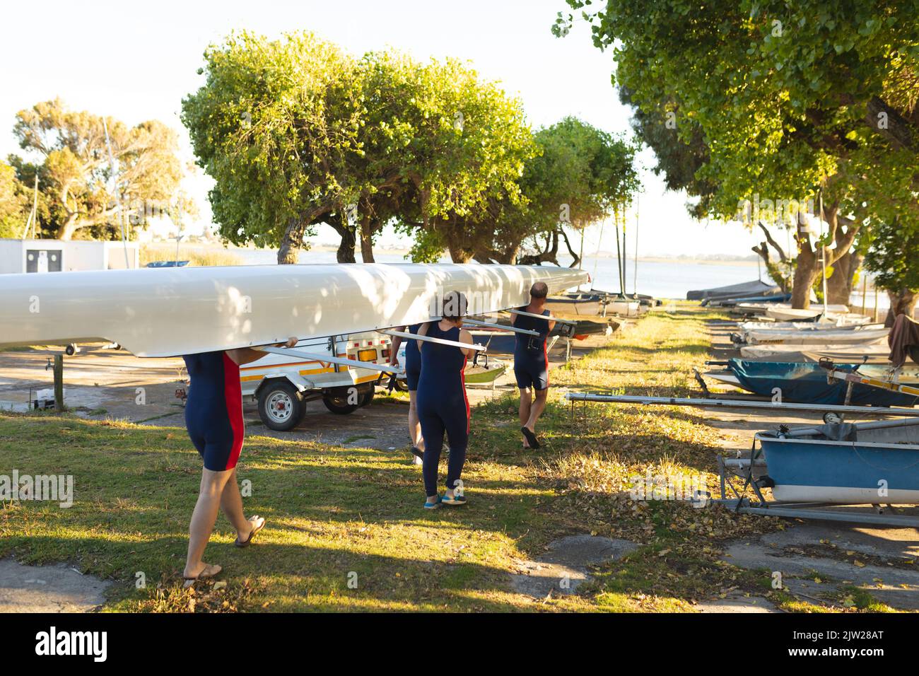 Rear view of senior caucasian rowing team carrying boat together to the ...