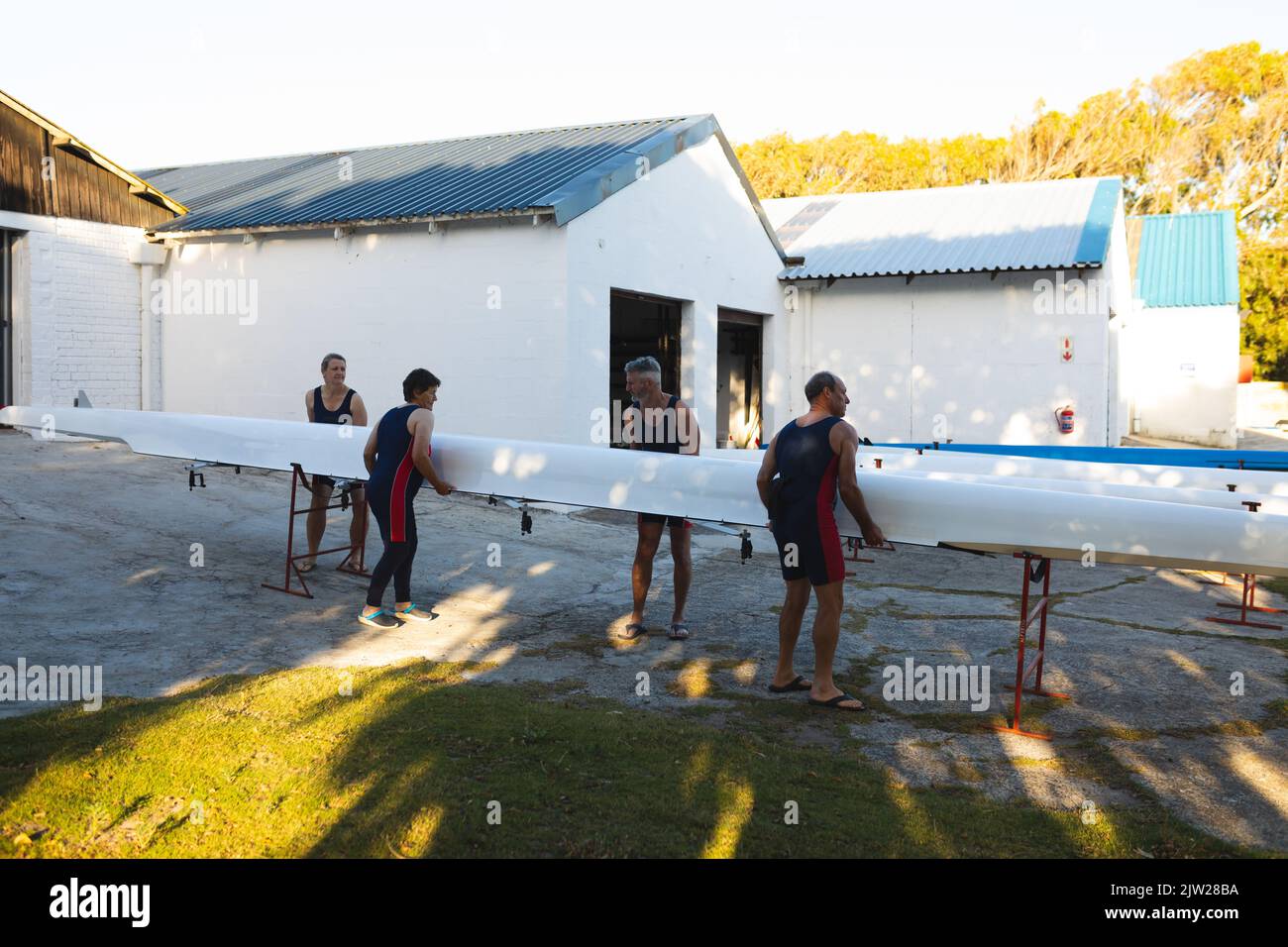 Senior caucasian rowing team carrying boat together to the lake Stock ...