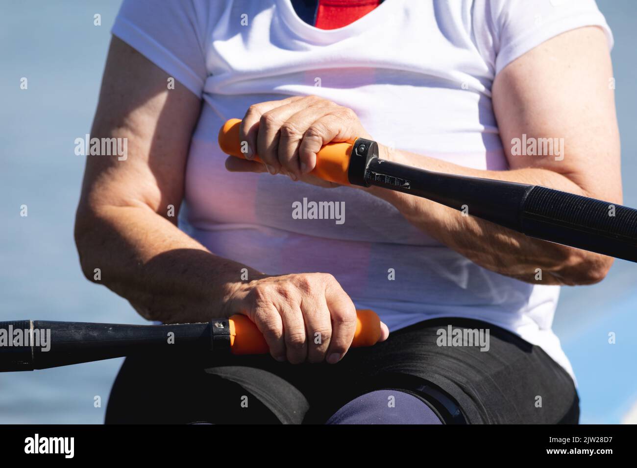 Mid section of senior caucasian female rower rowing the boat on the ...