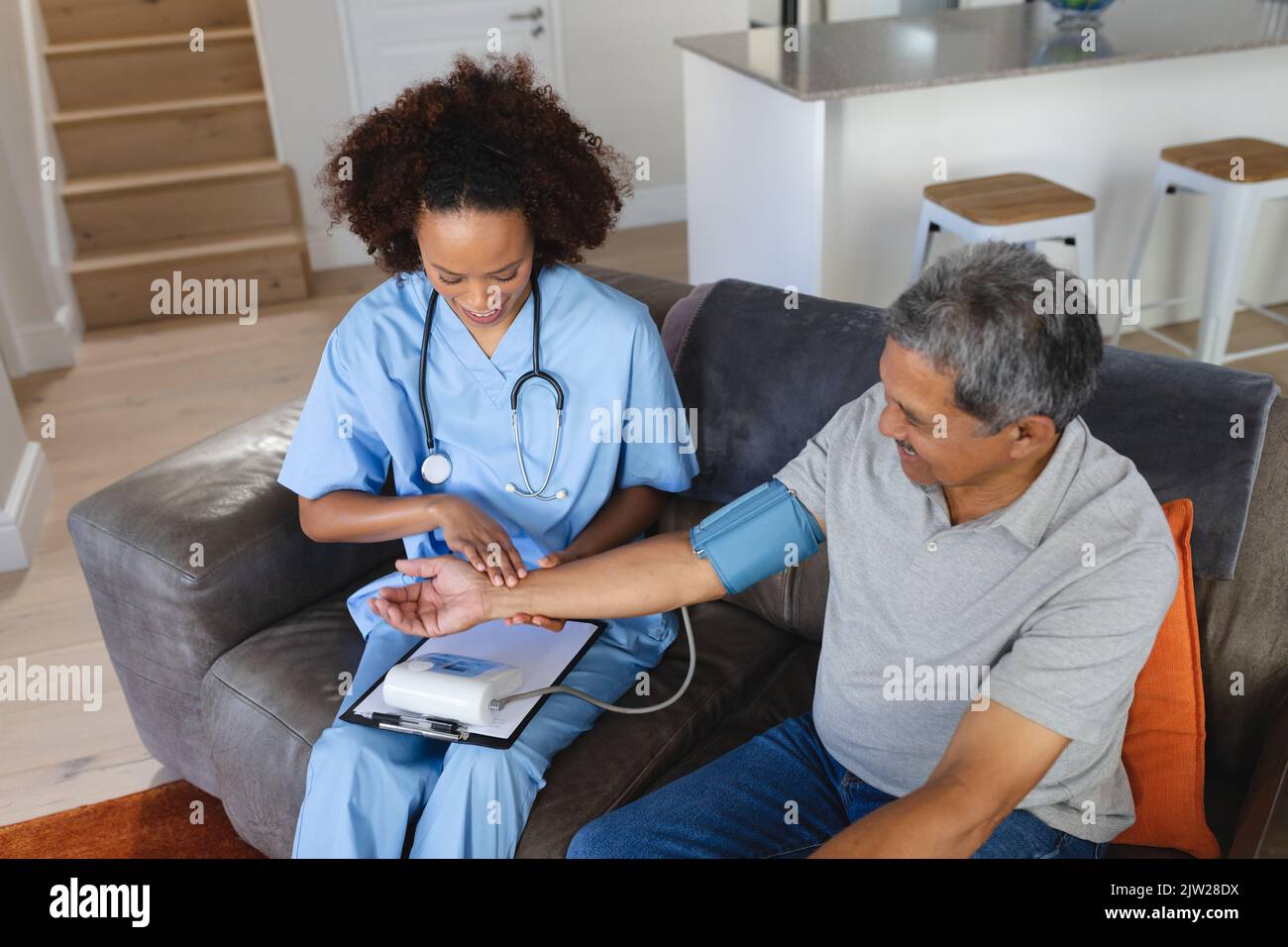Senior mixed race man with female doctor home visiting taking blood ...