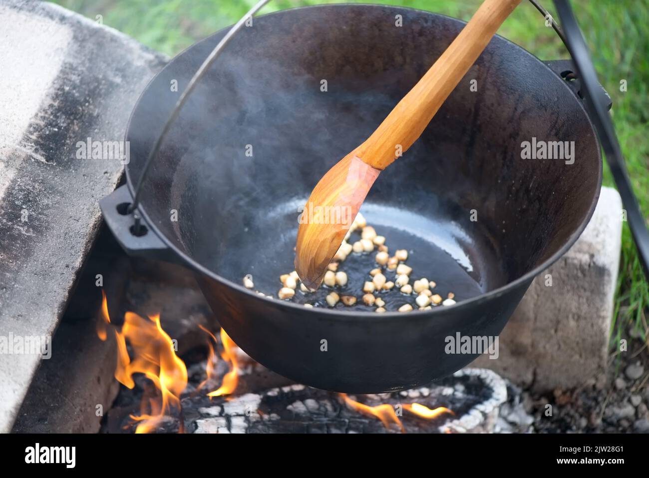 Big wooden spoon in a cauldron on fire Stock Photo - Alamy