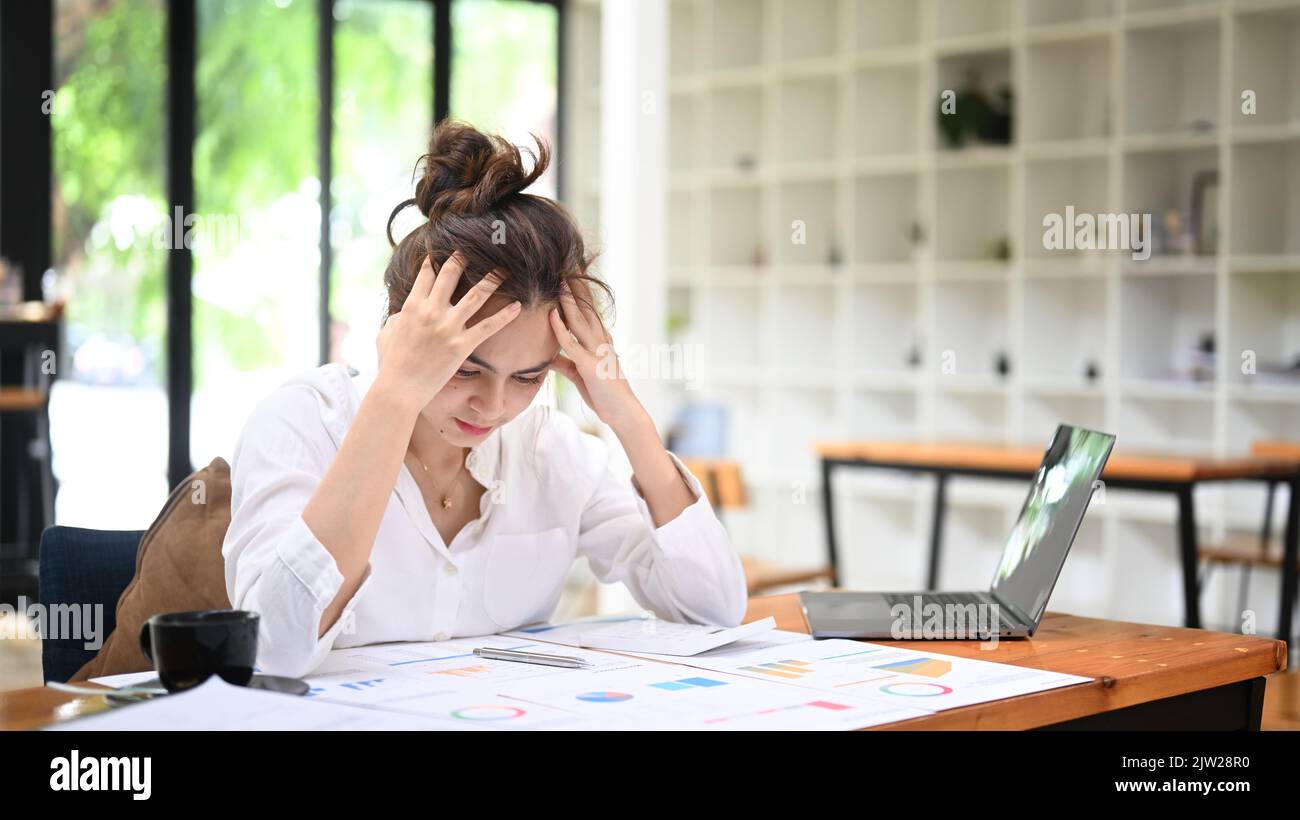 Frustrated female office worker holding her head, thinking find ...