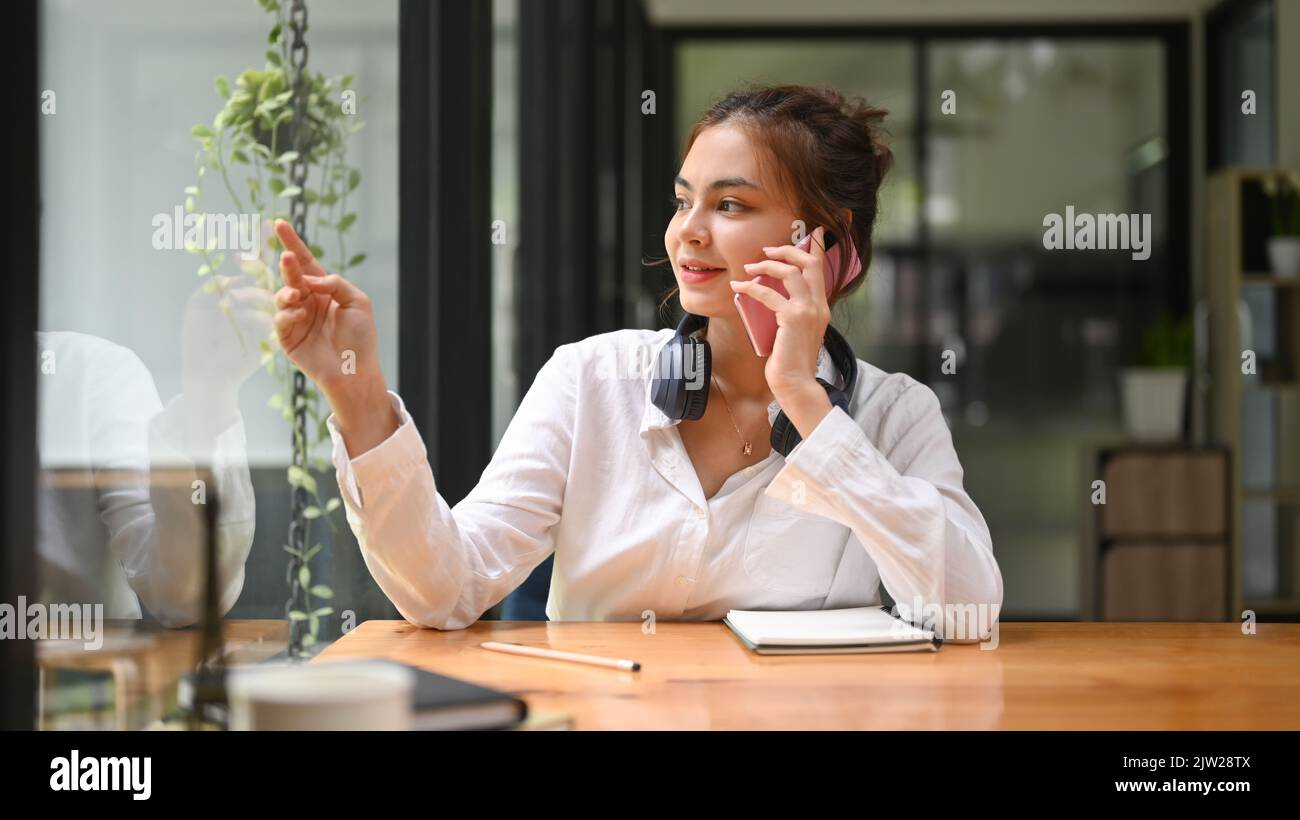 Pretty young woman having phone conversation and looking through office ...