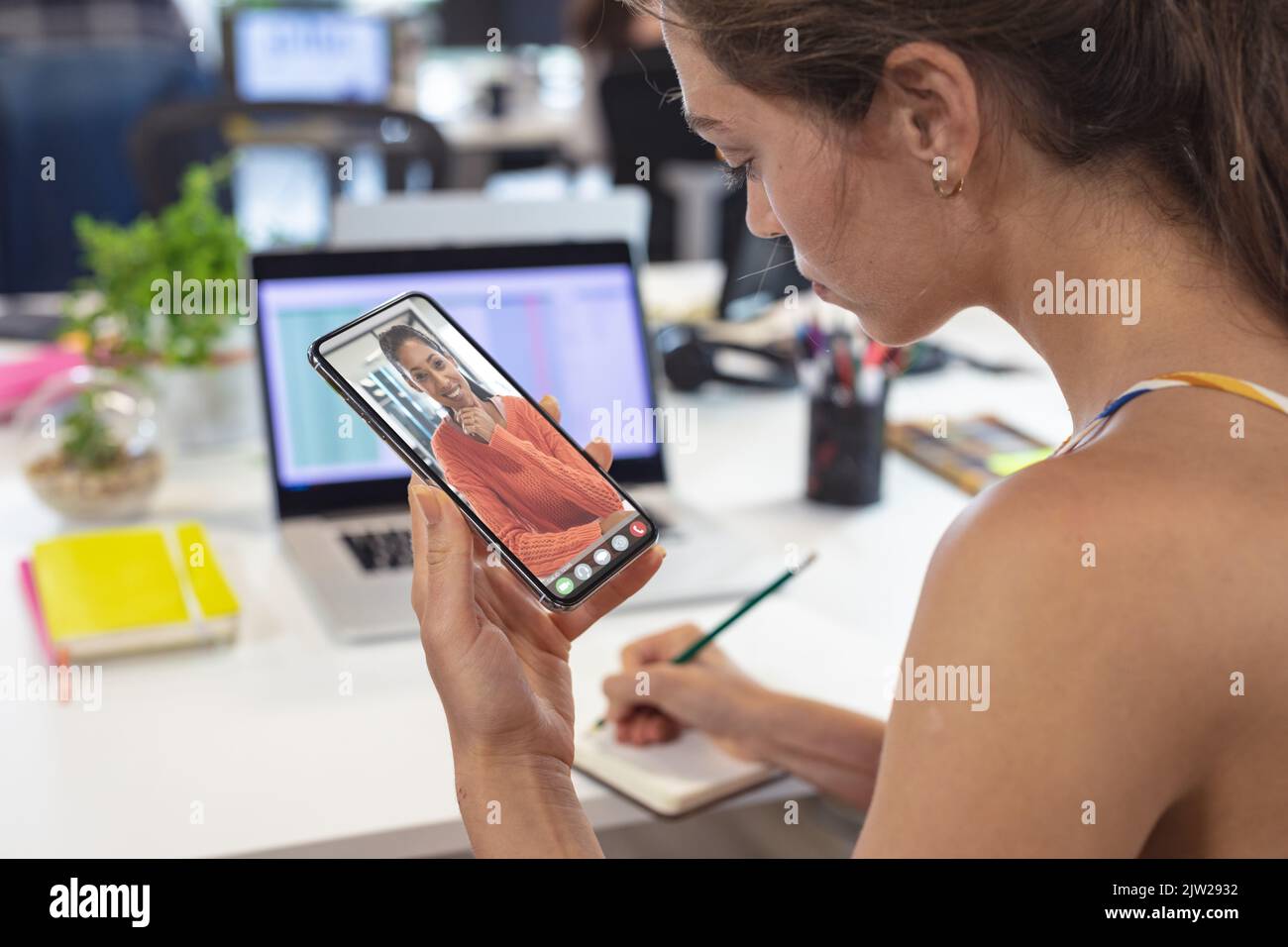 Caucasian businesswoman making notes while video calling female ...