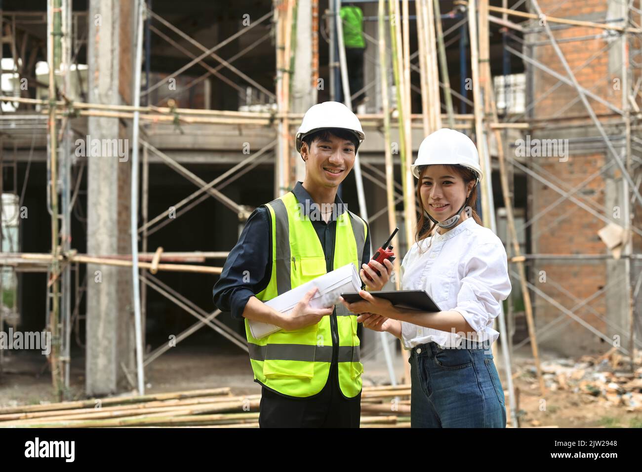 Female architects and engineer standing with arms crossed at construction site. Industry ...