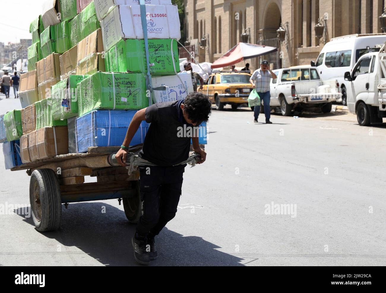 Baghdad, Iraq. 29th Aug, 2022. A boy pulls a cart loaded with goods in ...