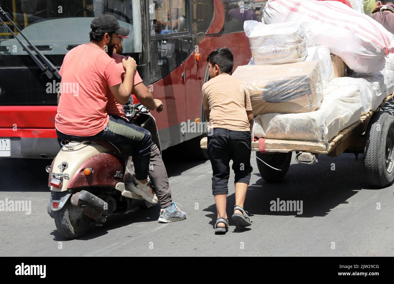 Baghdad, Iraq. 29th Aug, 2022. A boy pushes a cart loaded with goods at ...