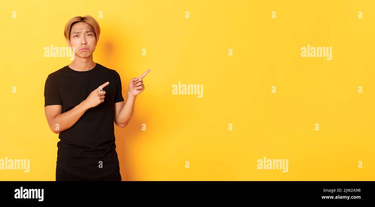 Portrait of disappointed and sad handsome blond asian guy, sulking ...