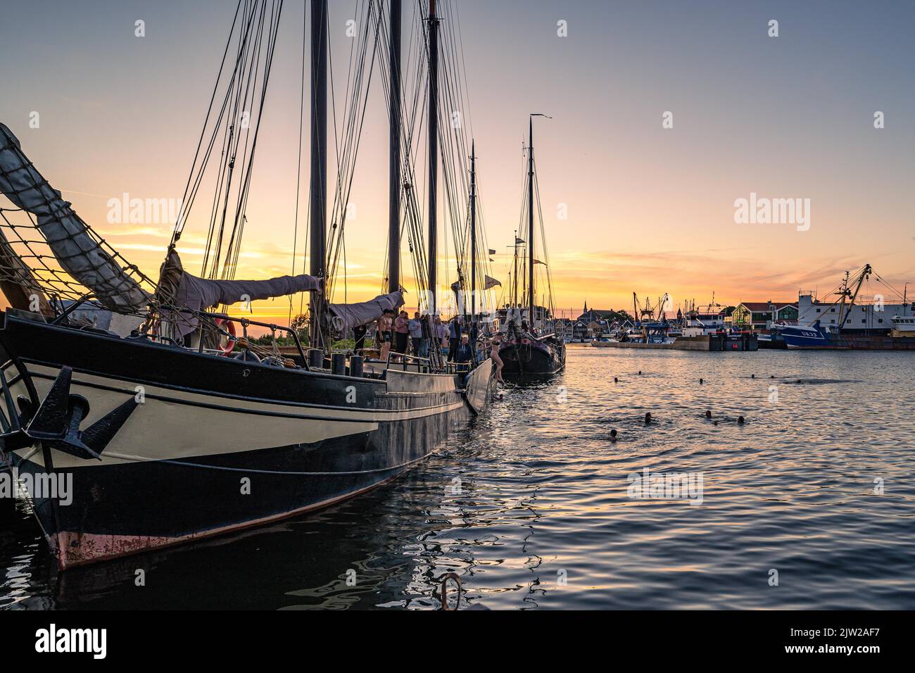 Sunset bathing among the sailing ships in the harbour, Urk, Ijsselmeer ...