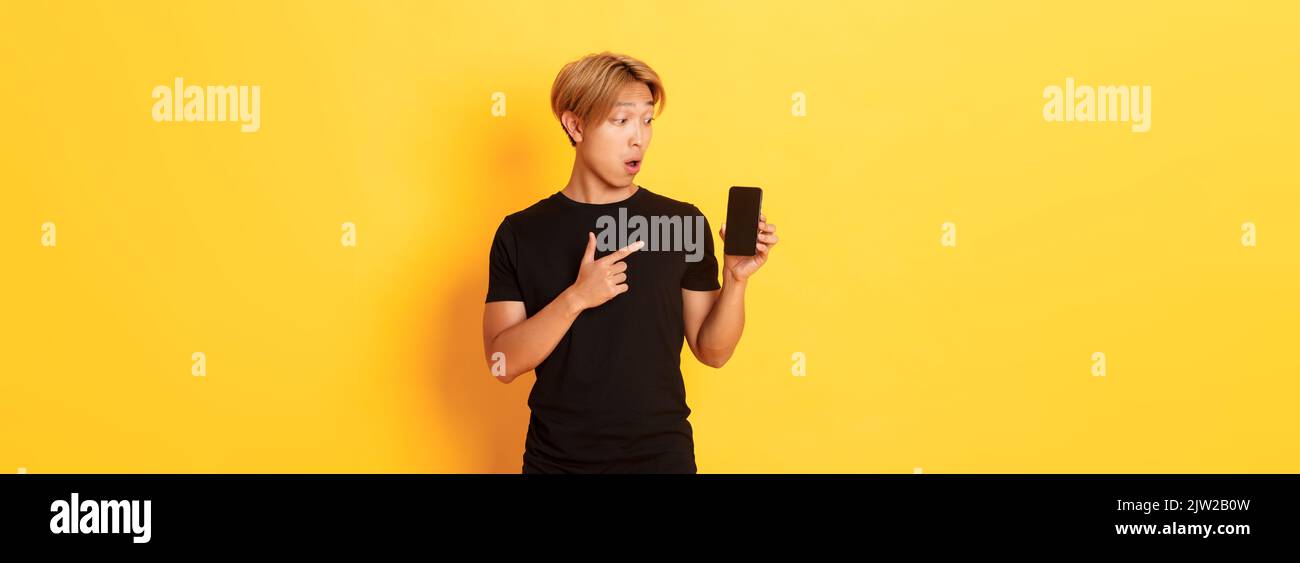 Portrait of handsome asian man showing something on smartphone screen ...