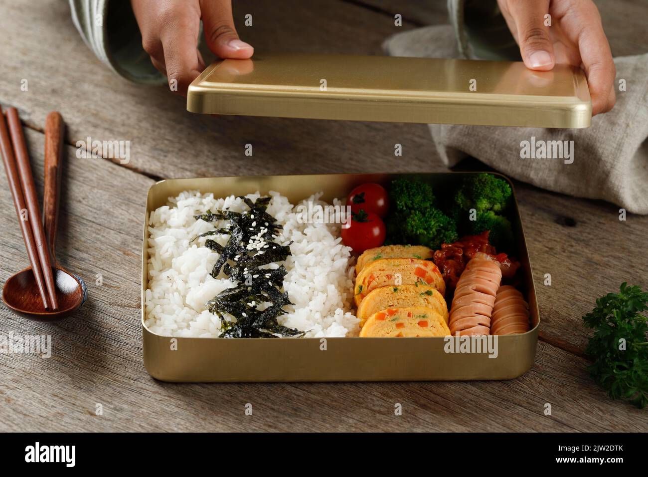 Female Hand Preparing Close the Lid Box of Dosirak or Korean Bento Box, Served on Gold Metal ...