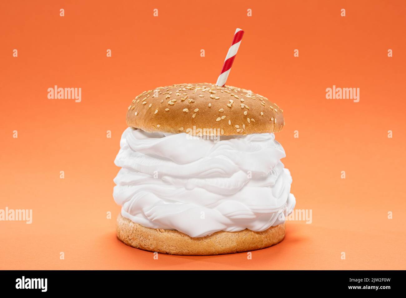 Halves of burger bun with sesame and sweet whipped cream and straw ...