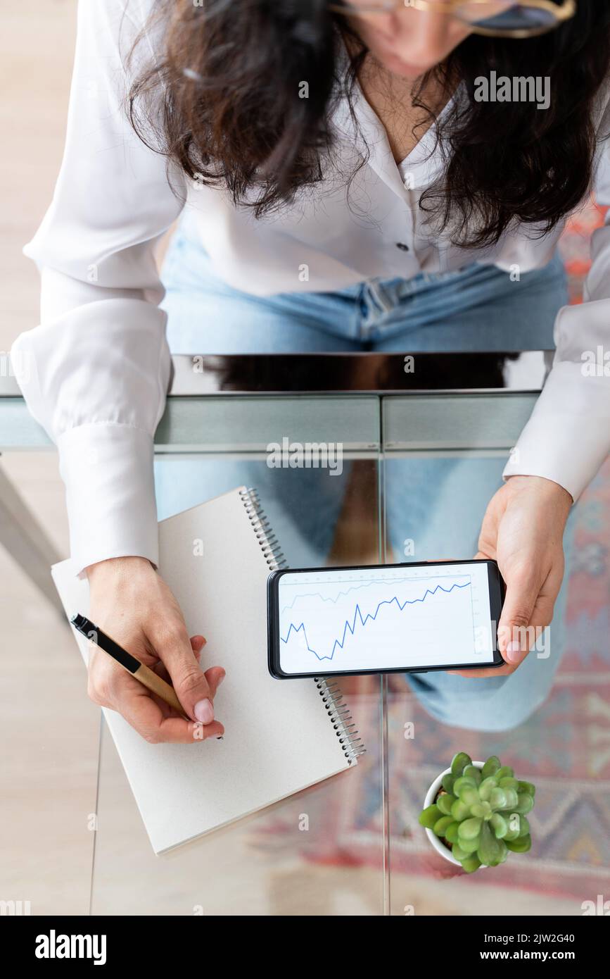 Top view of crop faceless female worker taking notes in notebook while ...