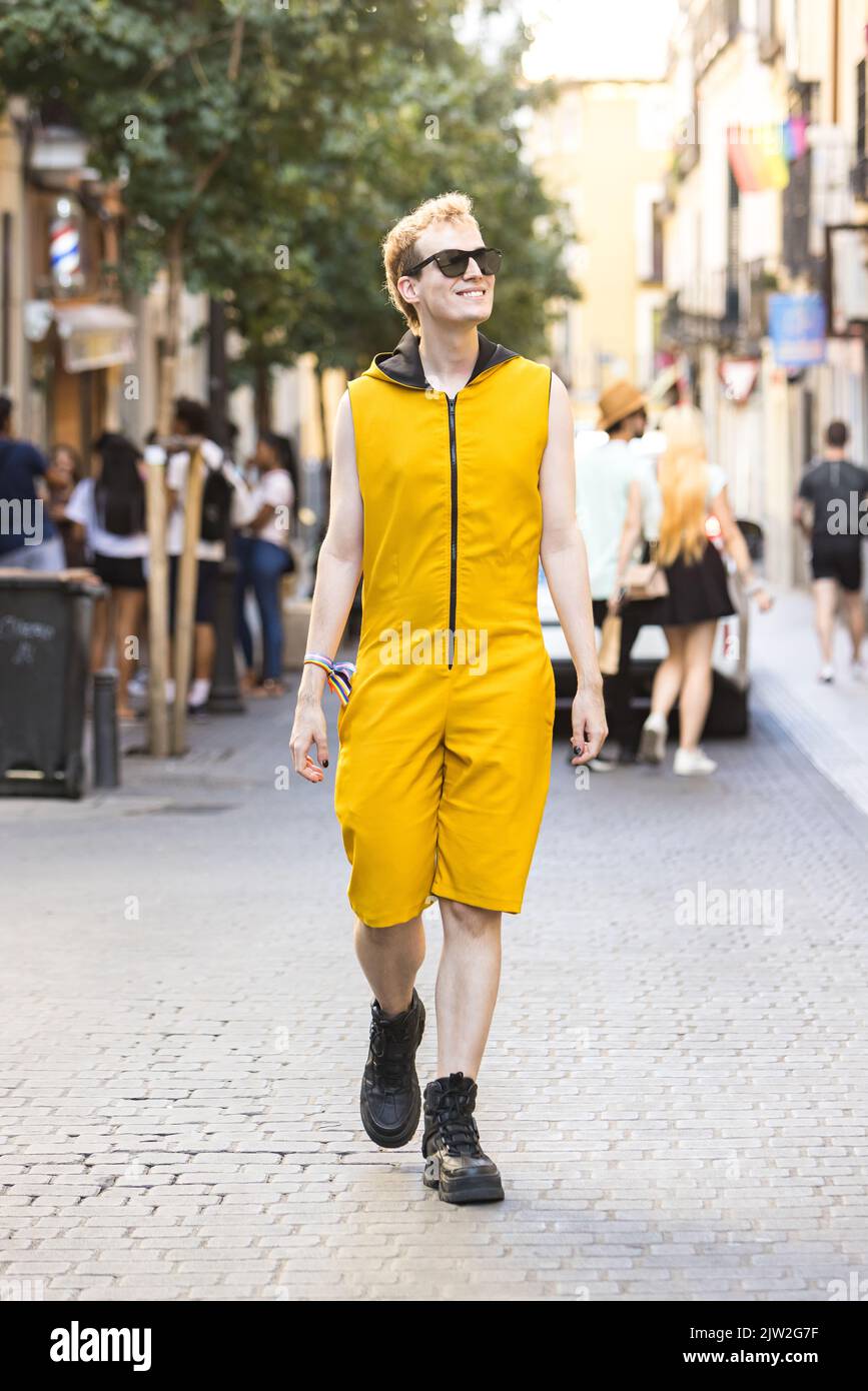 Full body cheerful transgender young man in yellow jumpsuit and ...