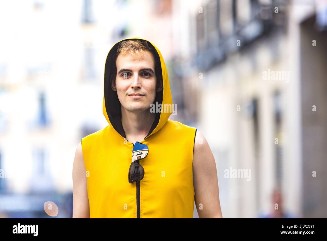 Transgender young man in yellow jumpsuit looking at camera while ...