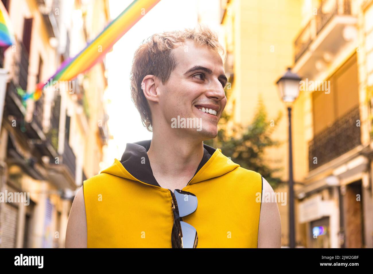 From below happy non binary male in stylish clothes smiling and looking ...