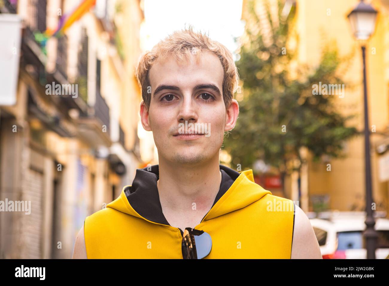 Serious non binary male in stylish clothes looking at camera on blurred ...