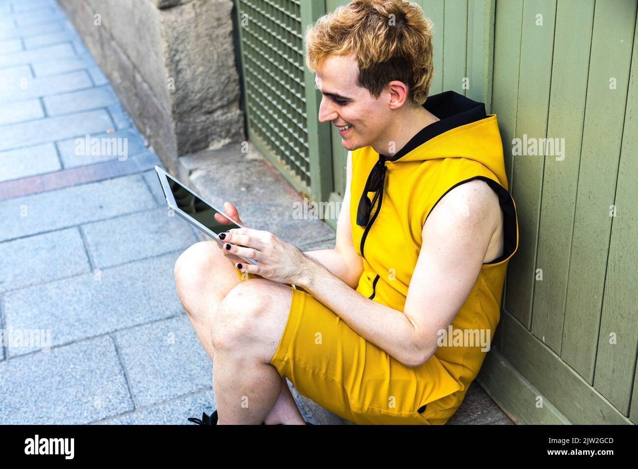 From above side view of young smiling transgender man in yellow ...