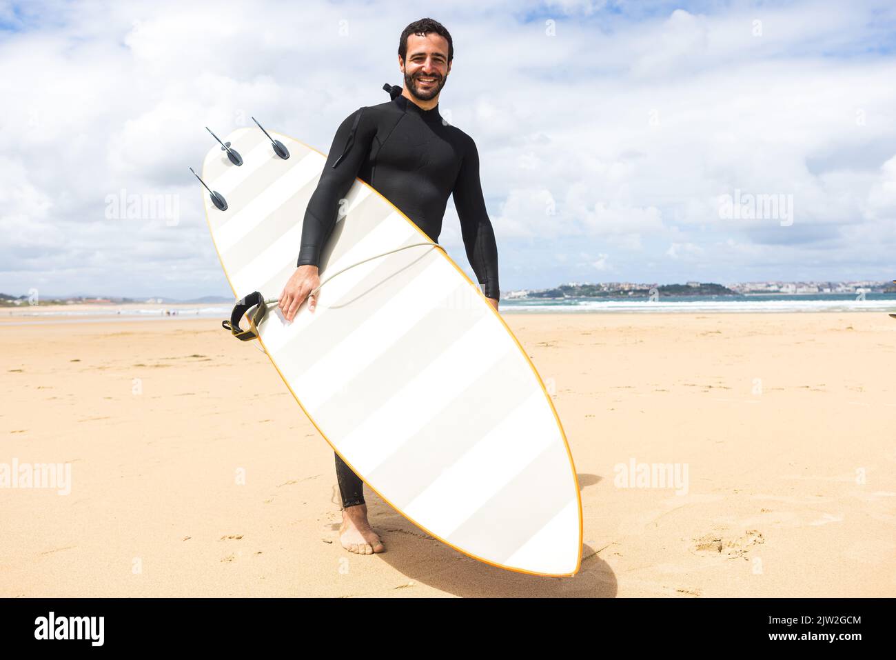 Full body of cheerful young Hispanic male surfer with dark hair and ...