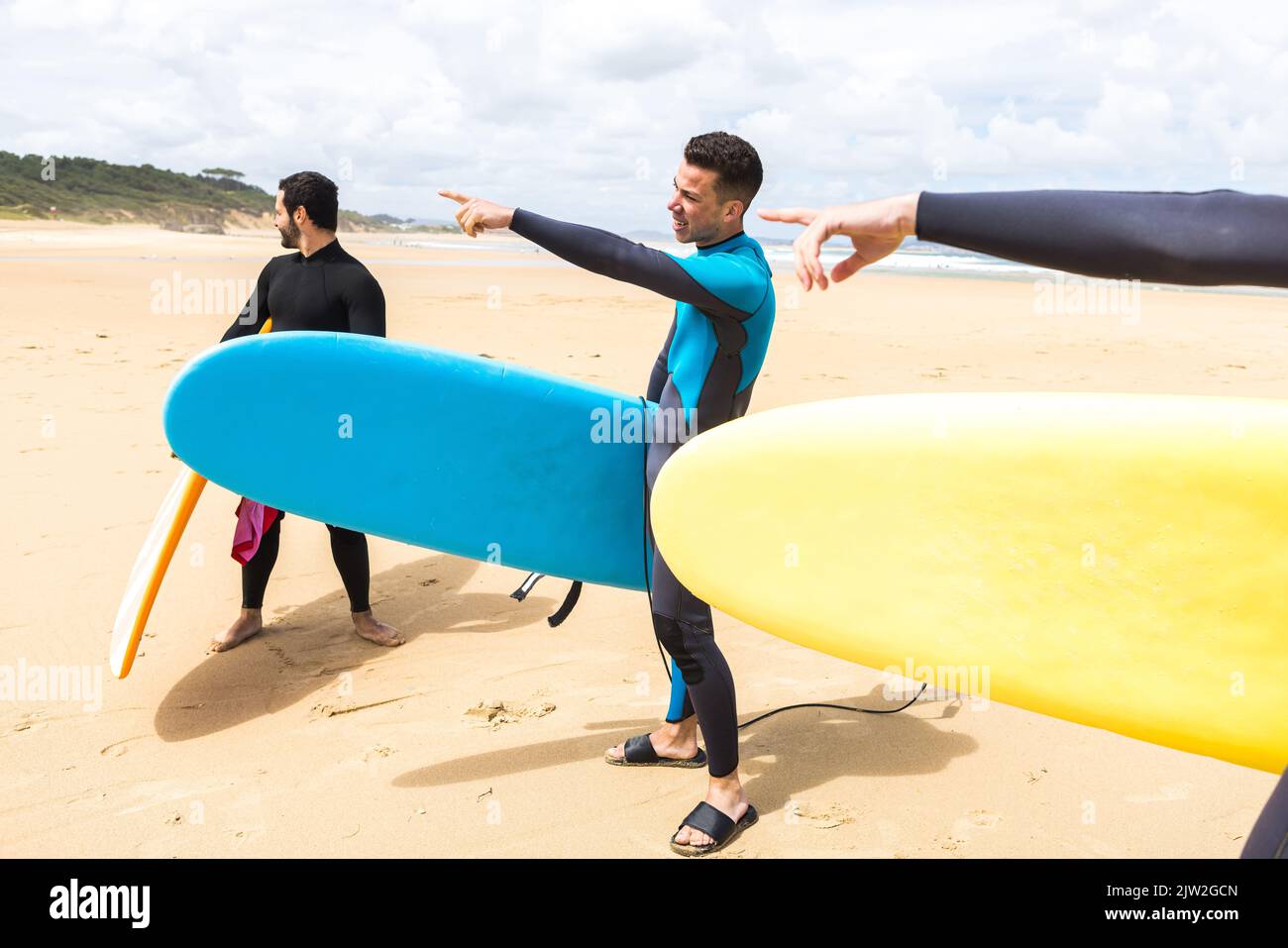Full body of young ethnic fit male surfers with dark hair in wetsuits ...