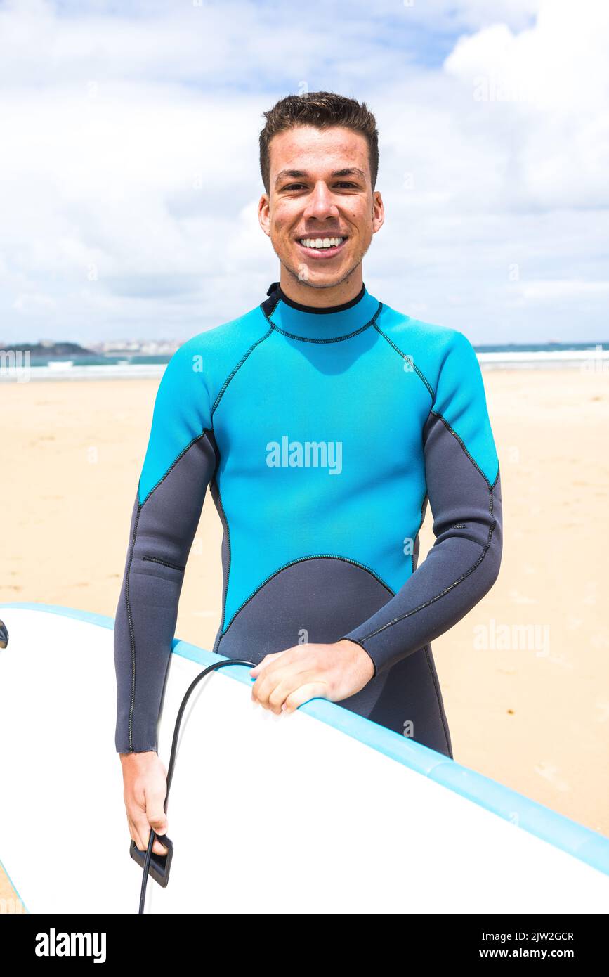 Cheerful young Hispanic male surfer with dark hair and in wetsuit ...