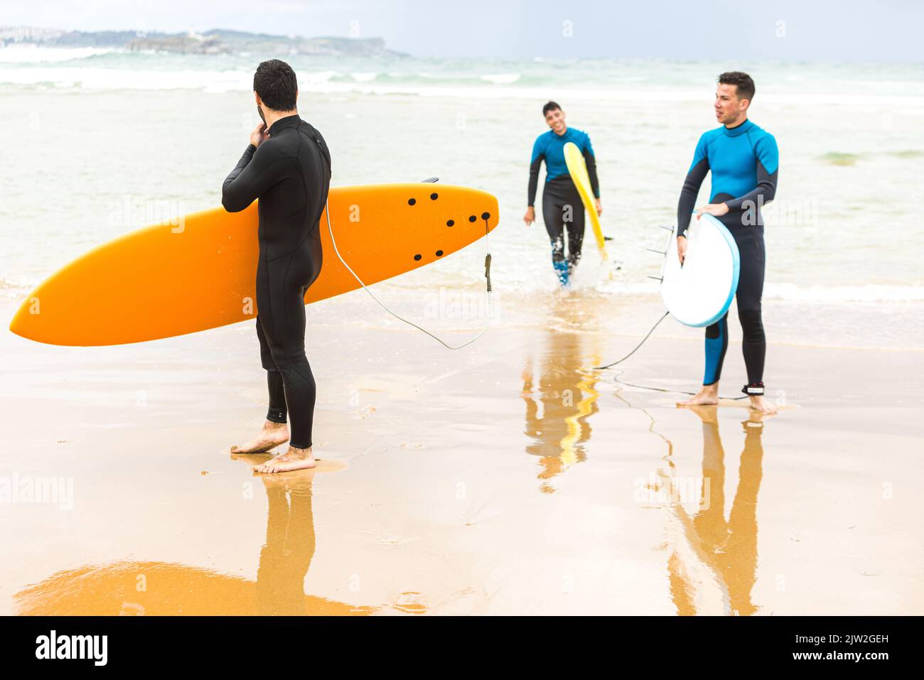 Positive fit young ethnic male friends with dark hair in wetsuits ...
