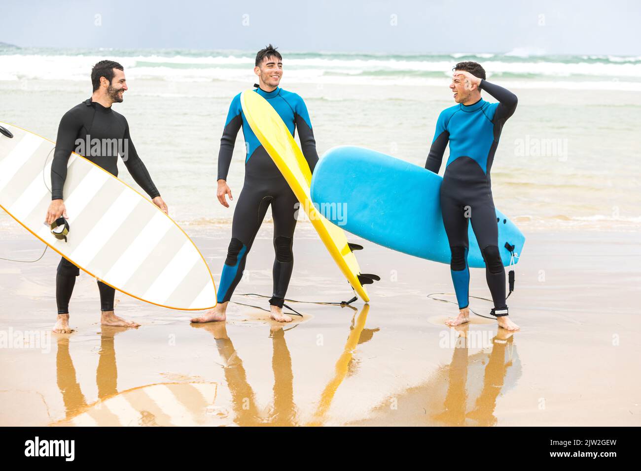 Positive fit young ethnic male friends with dark hair in wetsuits ...