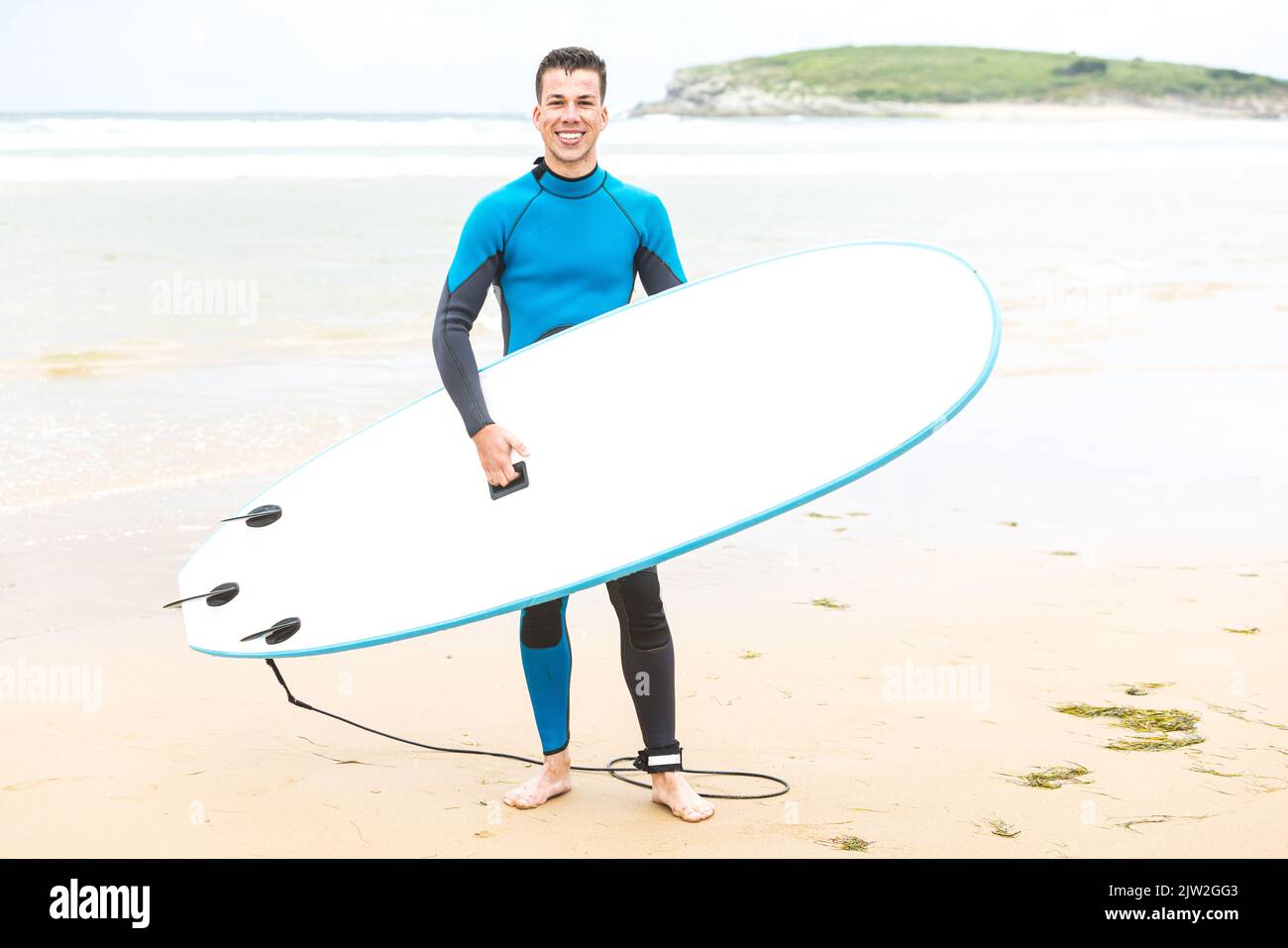 Full body of cheerful young Hispanic male surfer with dark hair and in ...