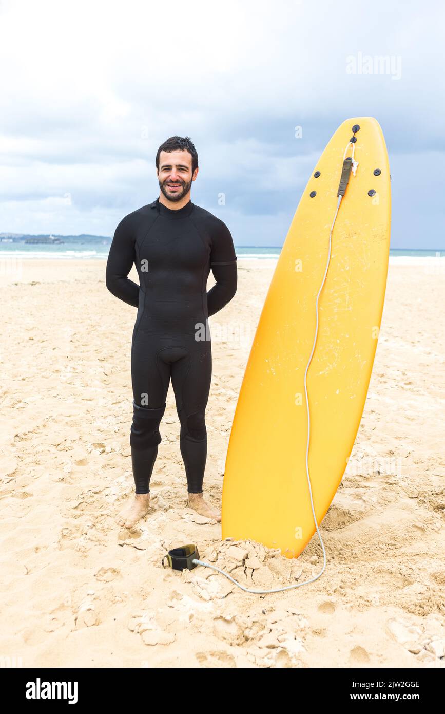 Full body of cheerful young Hispanic male surfer with dark hair and ...