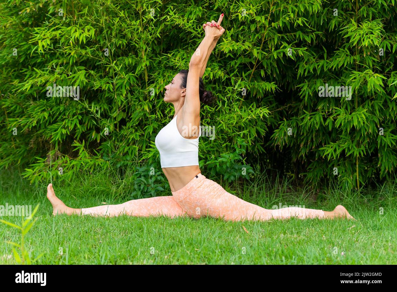 Full body side view of sportive female practicing Hanumanasana posture ...
