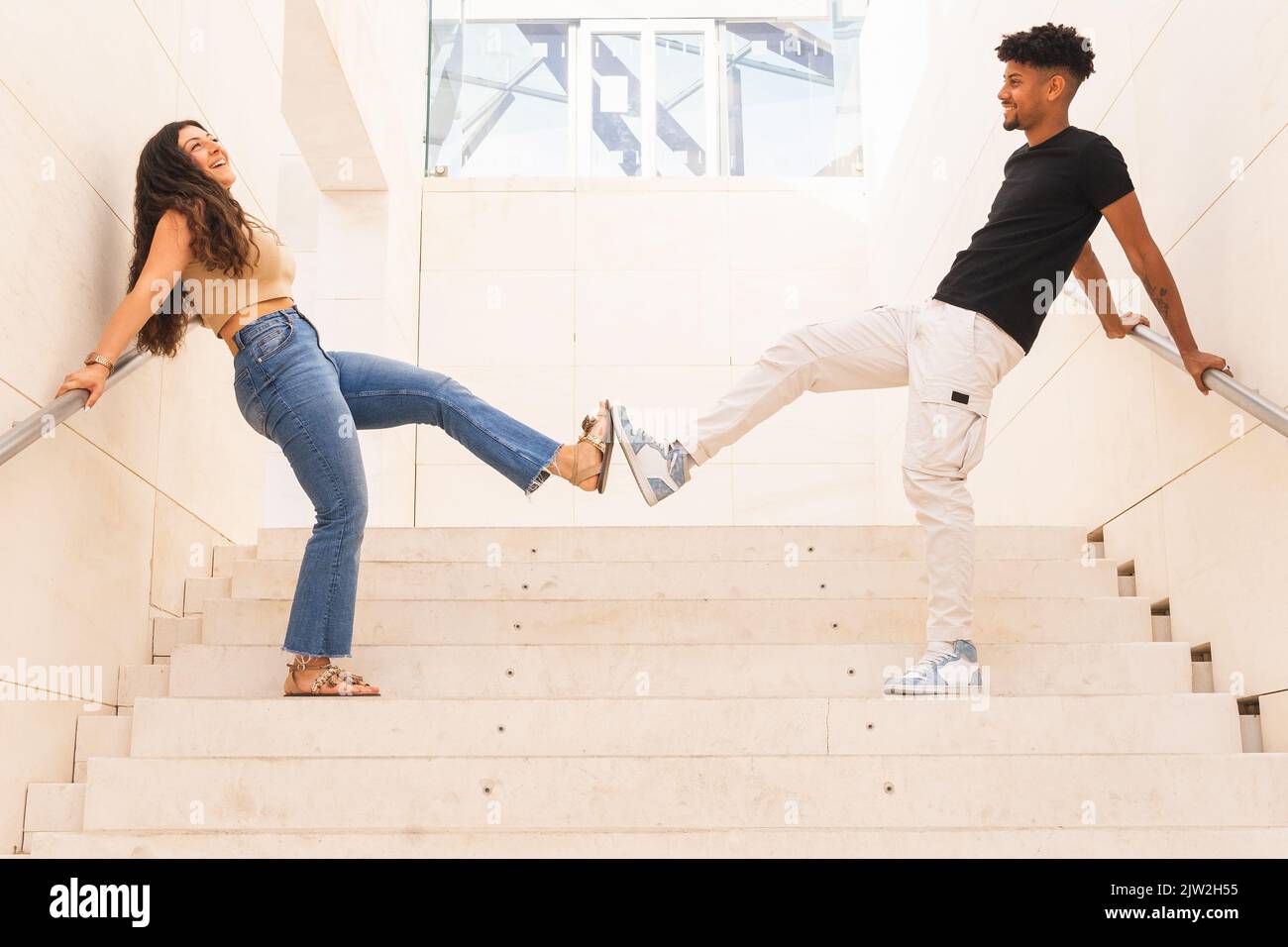 Full length of smiling young couple touching toes while standing on ...