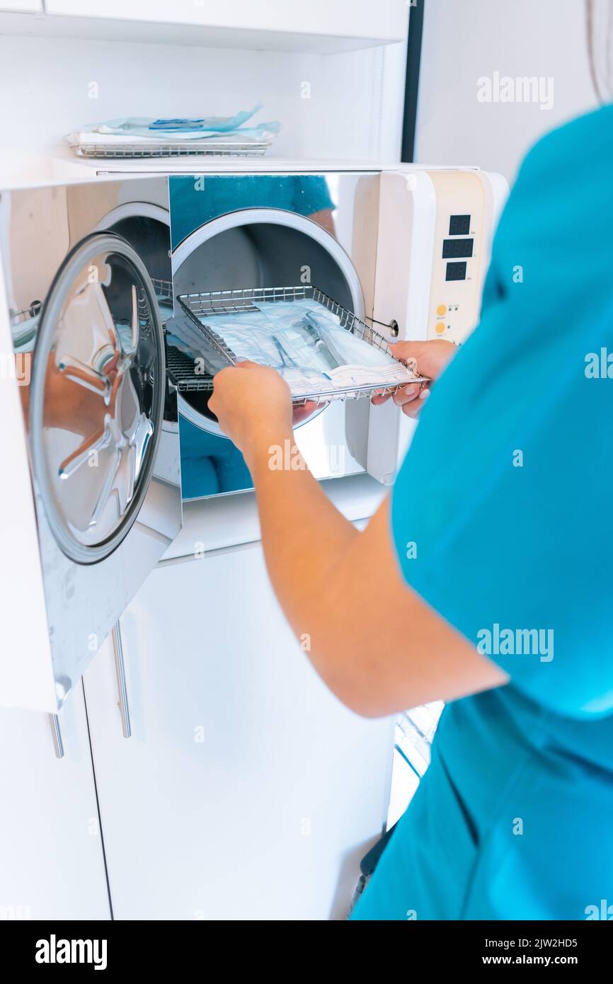 Crop unrecognizable female doctor in uniform sterilizing dental tools ...